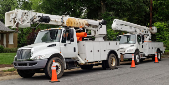 Front and side view of parked communication utility trucks in ...